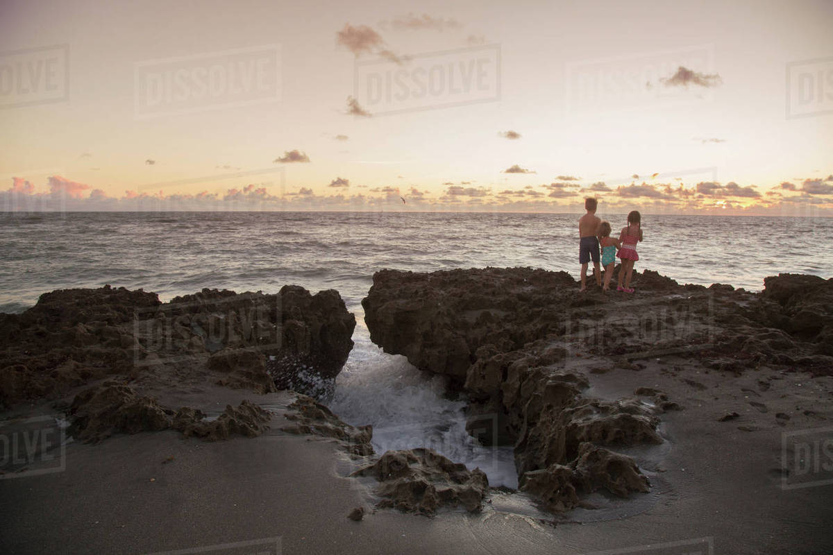 Boy and sisters looking out from rocks at sunrise, Blowing Rocks ...