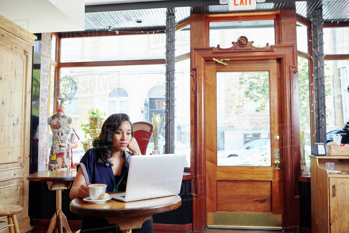 Young woman sitting in cafe, using laptop - Royalty-free Stock Photo ...