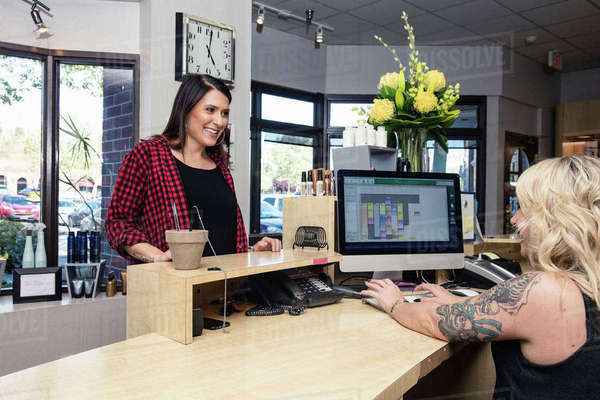 Receptionist attending to customer in hair salon - Stock Photo - Dissolve