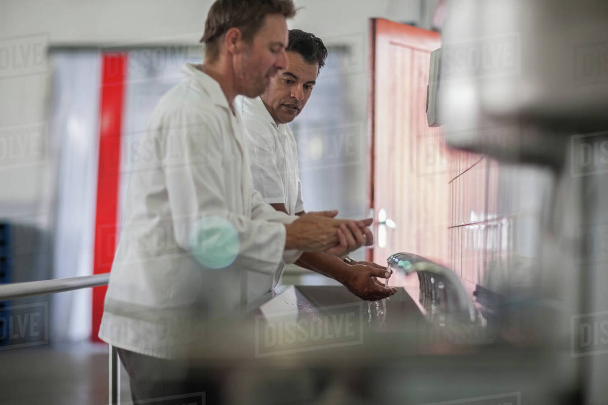 Two male factory workers washing hands in packaging factory - Royalty ...