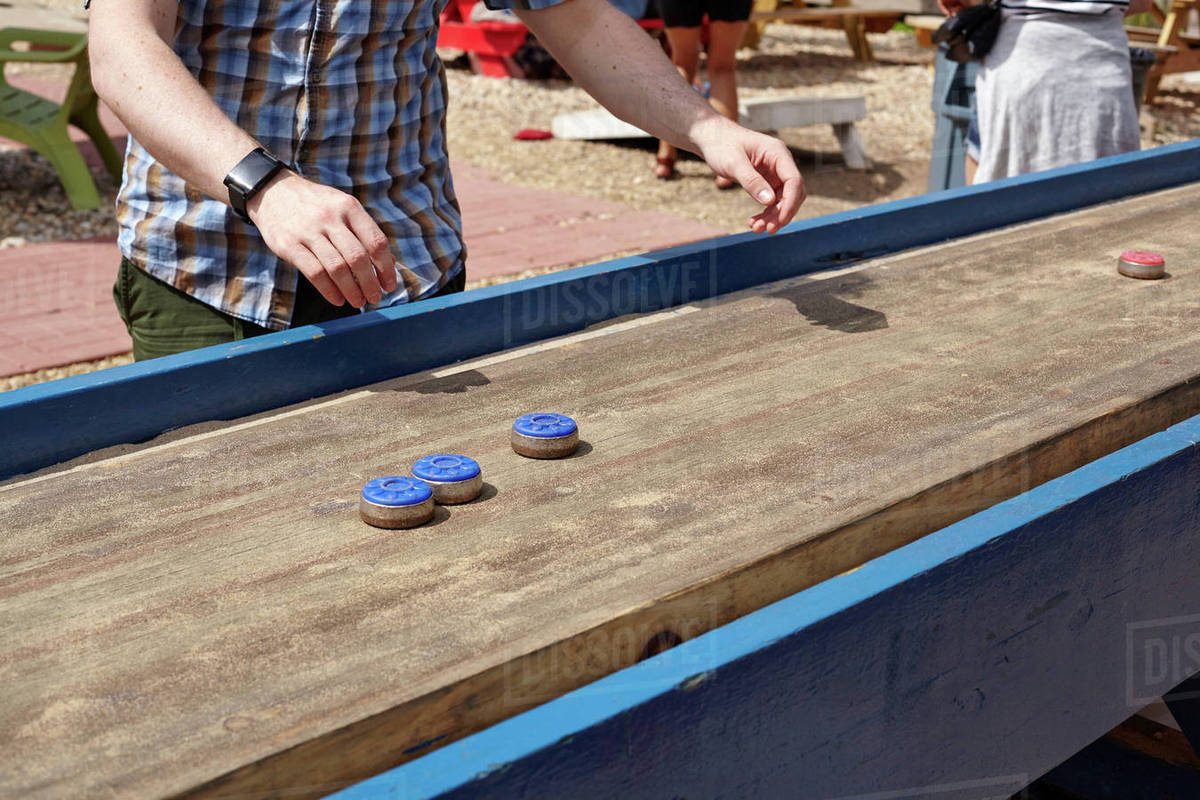 Young man playing table top shuffleboard, mid section - Royalty-free ...