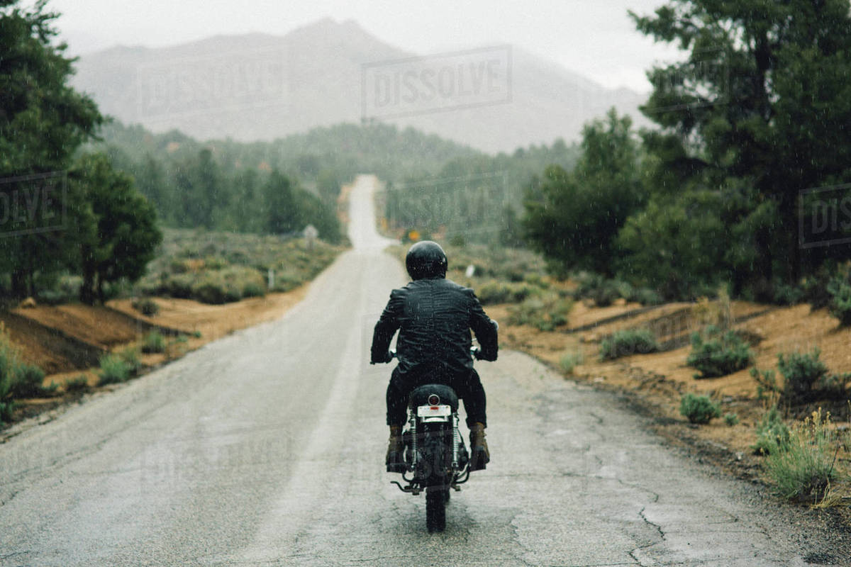 Rear view of motorcyclist riding motorbike on open road, Kennedy ...