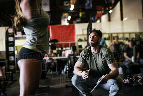Trainer observing cross training athlete exercising in gym - Stock ...