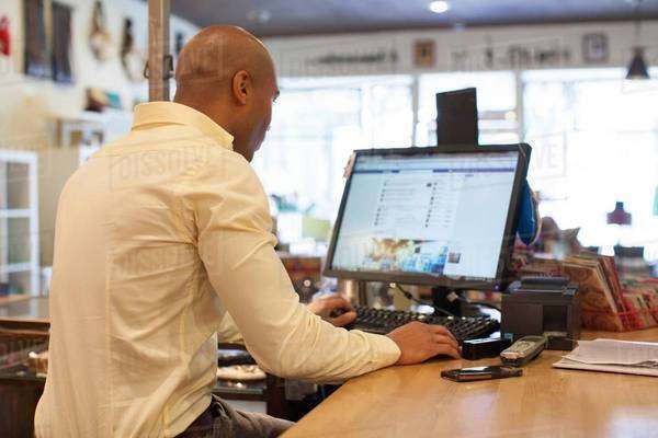 Shopkeeper using computer in vintage shop - Royalty-free Stock Photo ...