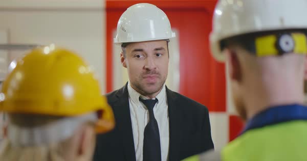 Close up back view of angry factory manager arguing with two engineers ...