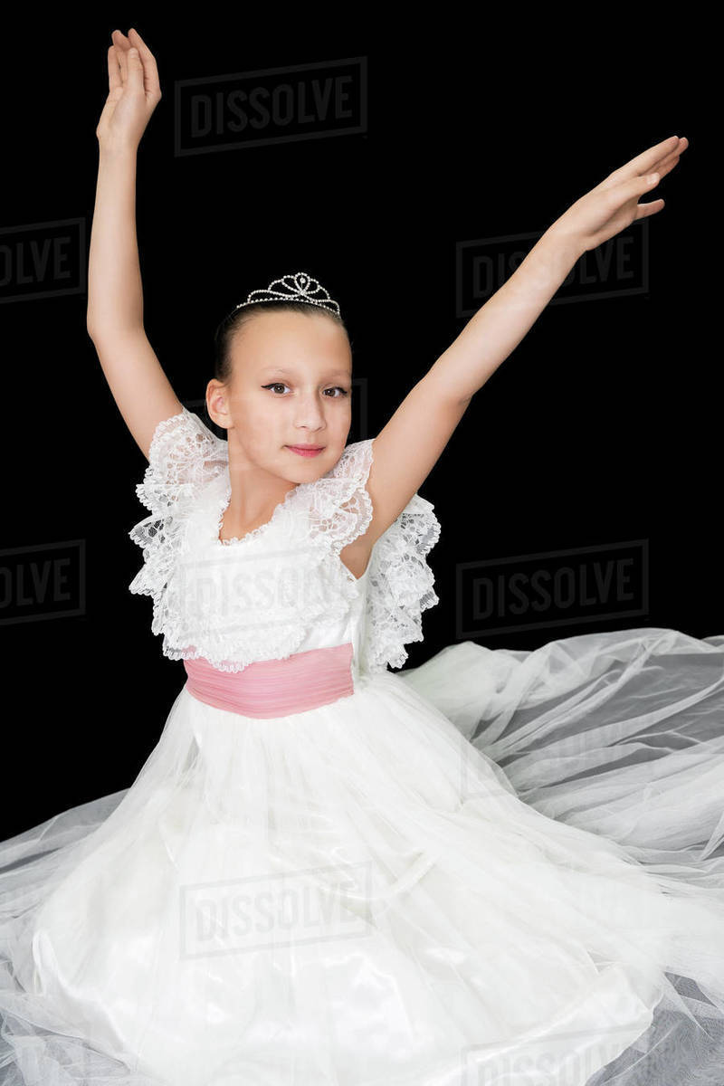 Girl ballerina in white long dress sitting on black background and ...