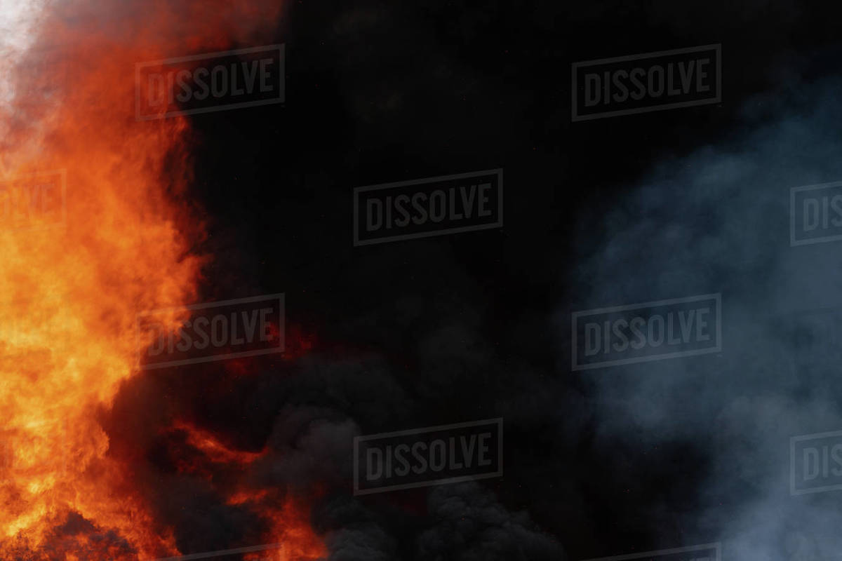 Dangerous huge flames of red fire, motion blur clouds of dark smoke ...