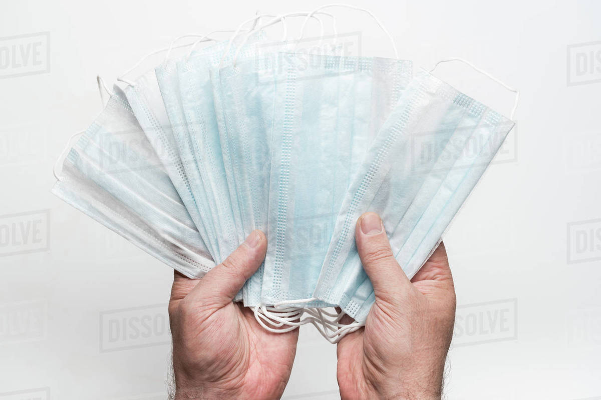Male patient holding lot medical face mask in hands on white background ...