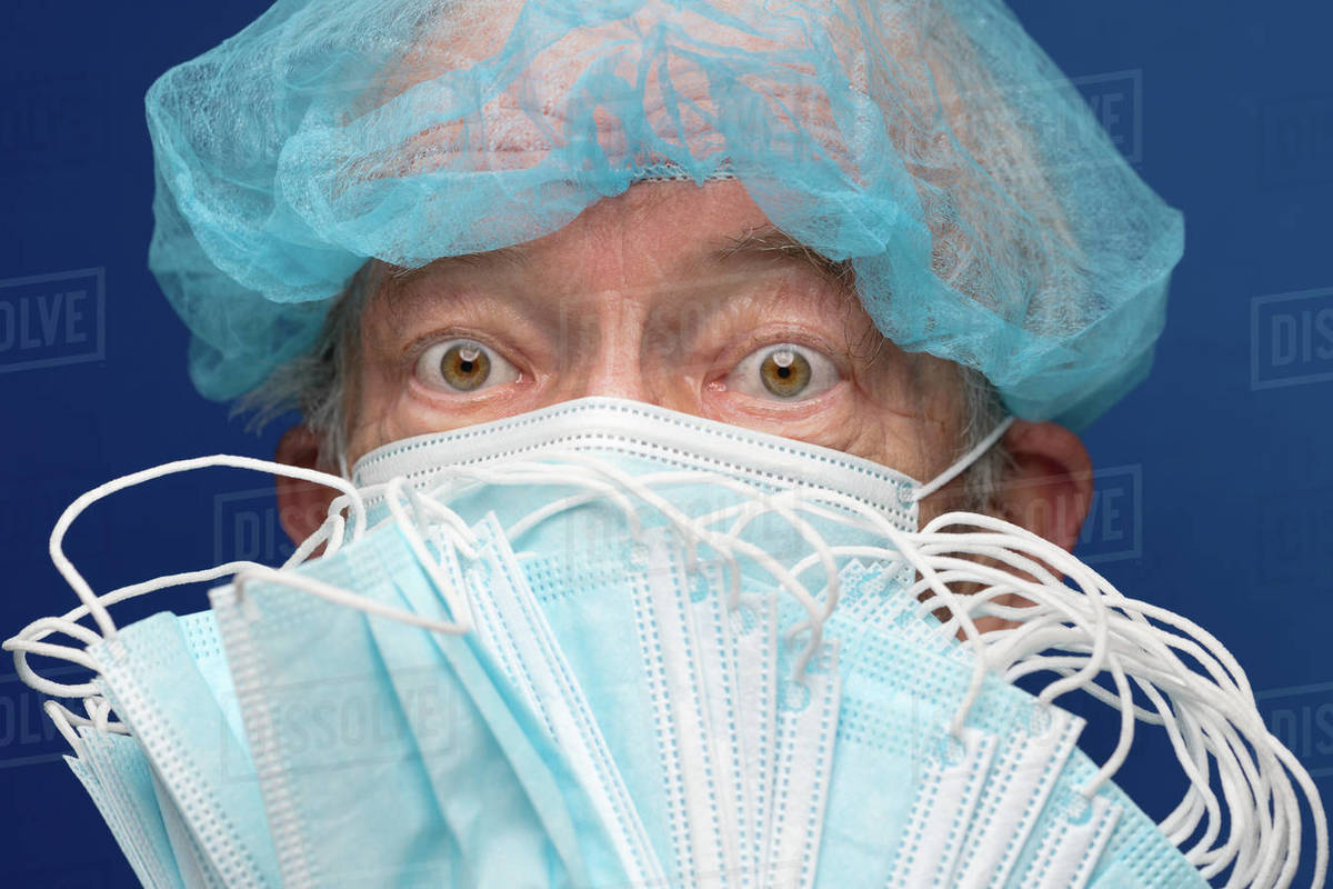 Portrait of senior adult fearful glance in medical face mask covering ...