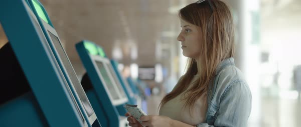 Woman using self check in desk screen at the airport terminal ...