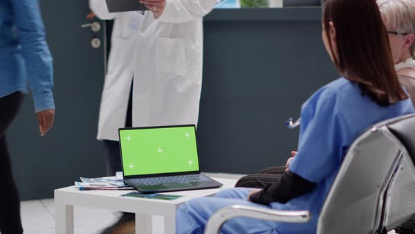 People sitting in waiting area with greenscreen template on laptop ...