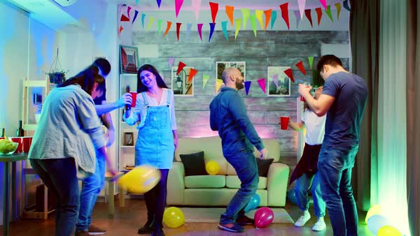 Group of young people dancing together at a party with neon lights and ...