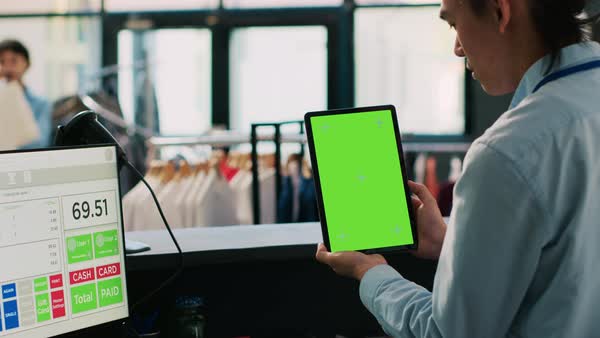 Asian store worker looking at chroma key green screen mock up tablet ...