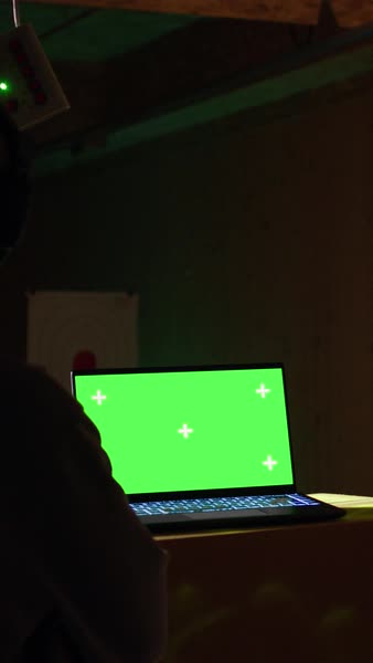 Vertical video Green screen laptop in shooting range next to man ...