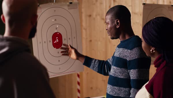 Shooting range safety officer explaining bullseye scoring system to ...