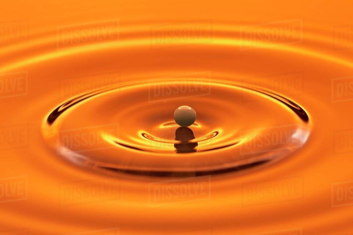 An abstract studio photo of a water drop splashing into still water ...