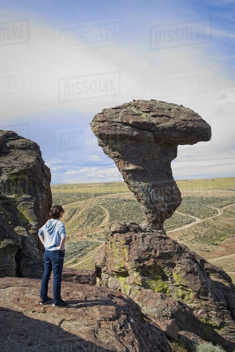A young woman stands on a rock ledge looking at the famous Balanced ...