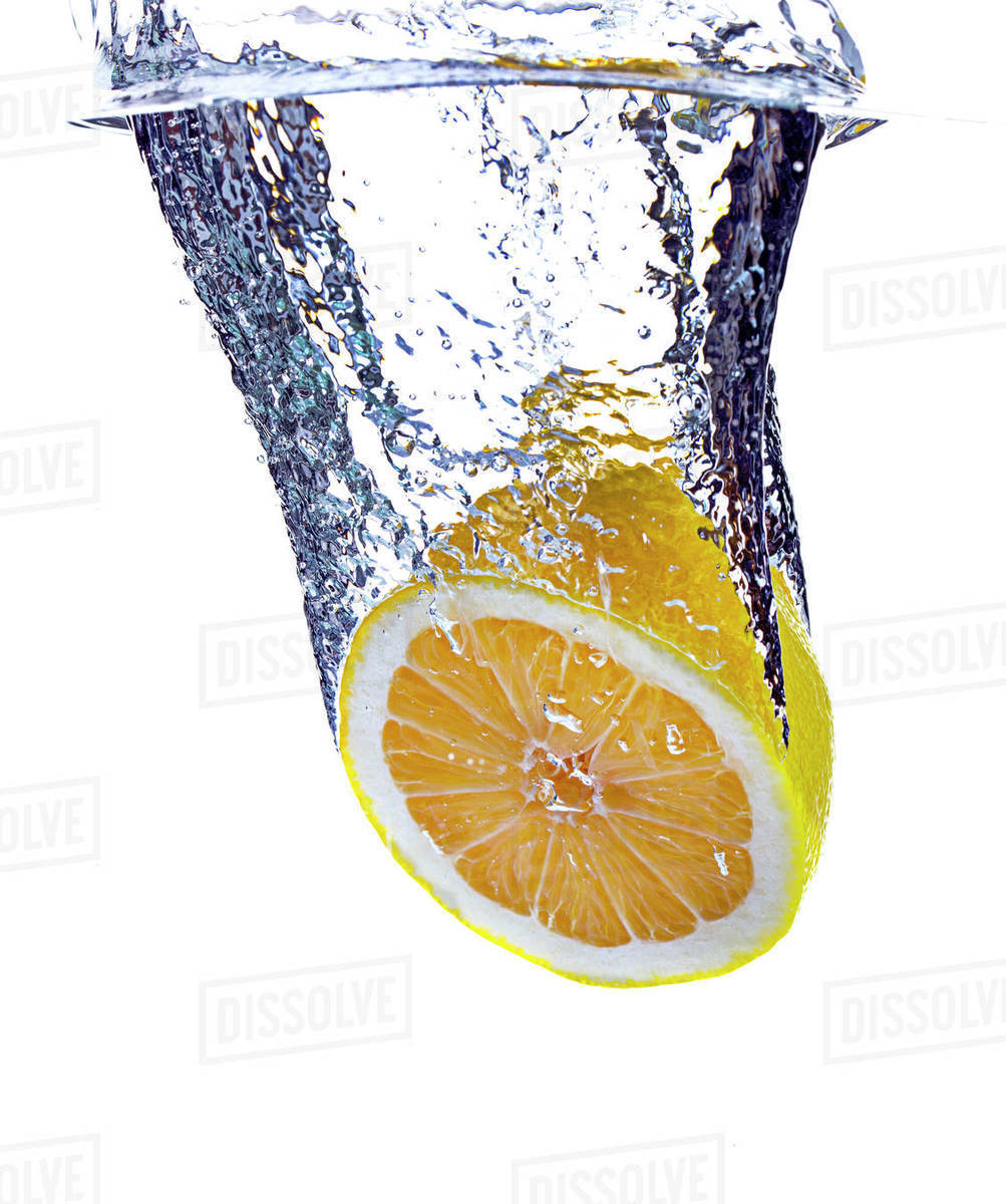 A lemon half is dropped into water against a white background. - Stock ...