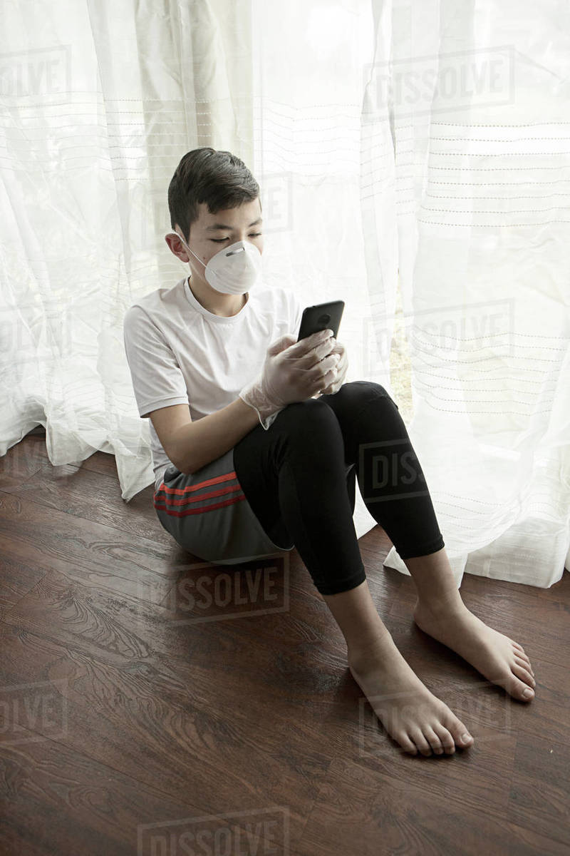 A concept photo of a teen boy with a mask, gloves, and a cell phone ...