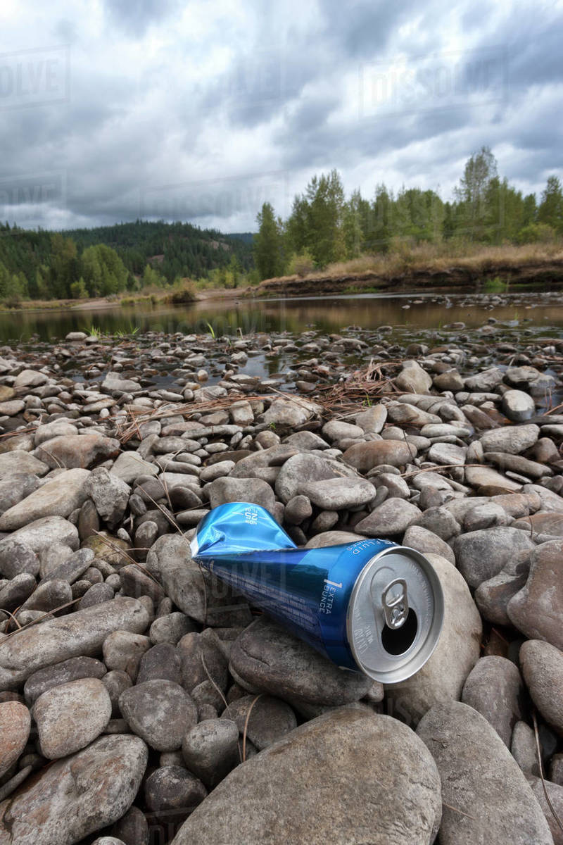 A conceptual image of an aluminum can littered on a rock river bed in ...