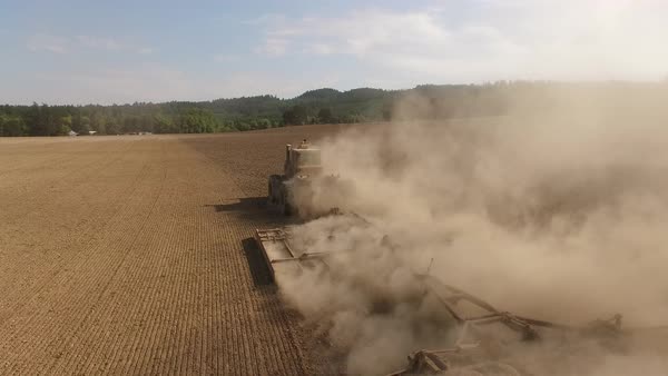 Tractor plowing dusty field aerial view - Stock Video Footage - Dissolve