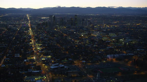 Aerial view of Denver at night with Rocky Mountains in background ...