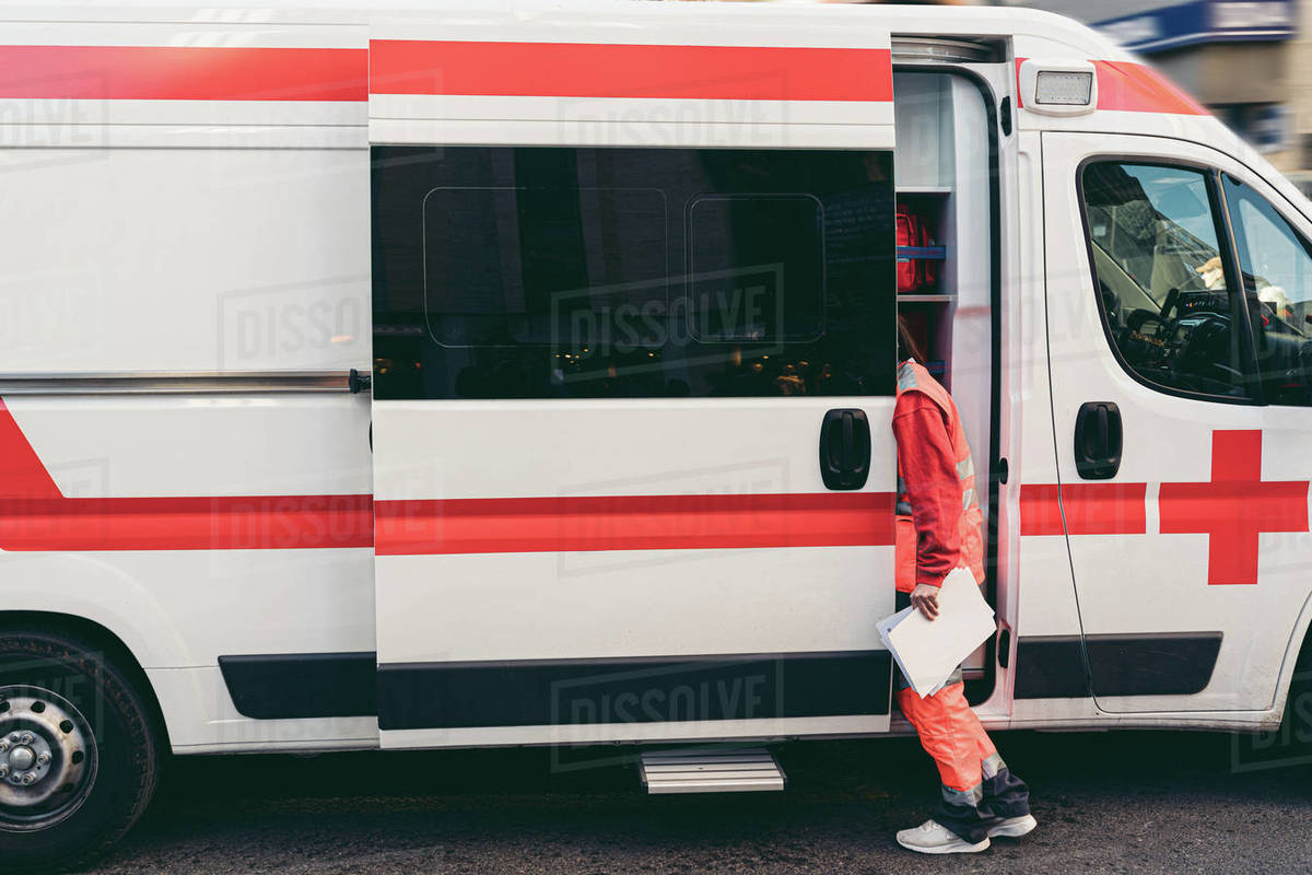 Red cross paramedic getting into ambulance van. - Stock Photo - Dissolve