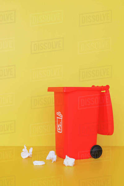 Red garbage container on yellow background - Stock Photo - Dissolve