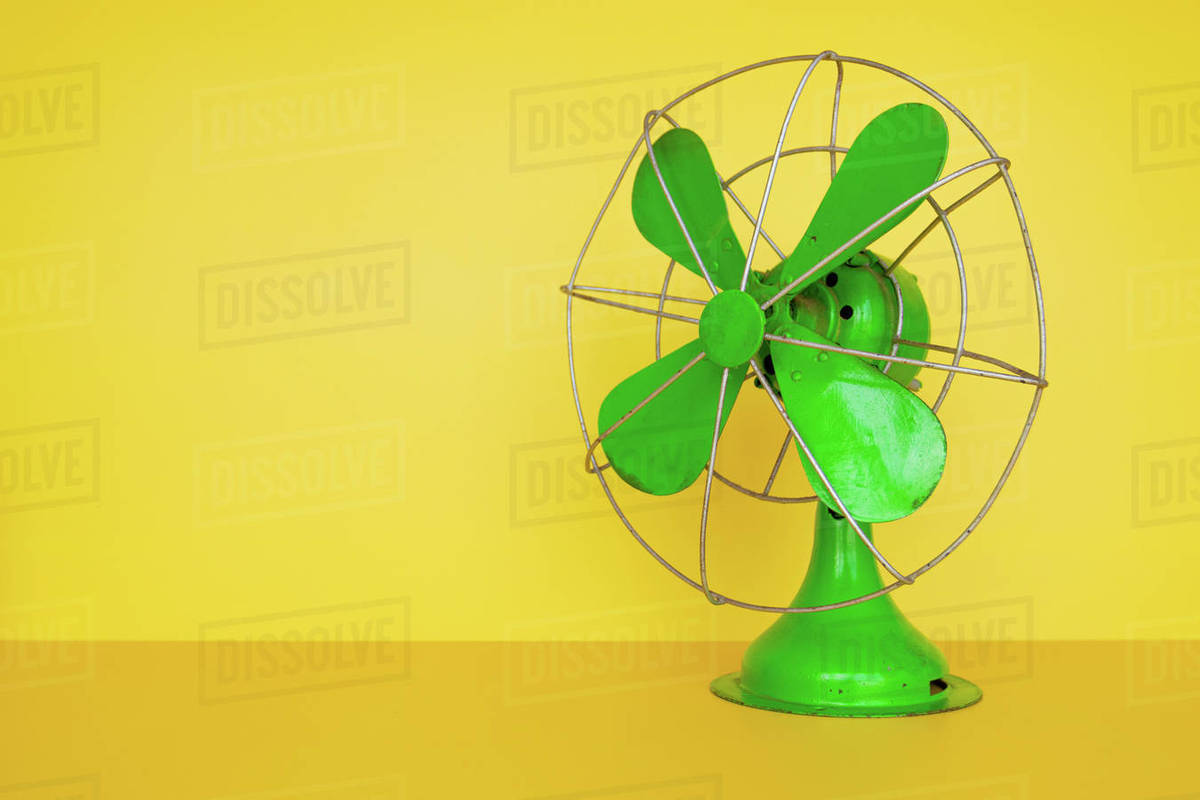 Old green electric fan on yellow background - Stock Photo - Dissolve
