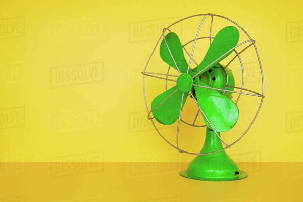 Old green electric fan on yellow background - Stock Photo - Dissolve
