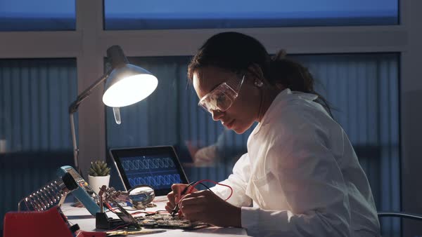 Side view of female electronics engineer working with multimeter tester ...