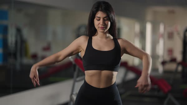 Female Middle Eastern bodybuilder turning boasting muscles looking at ...