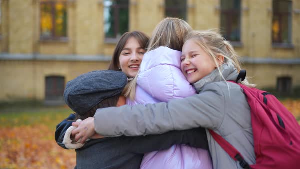 Beautiful teen girl hugging friends meeting with classmates on ...