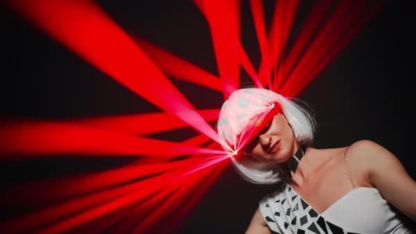 Flexible talented woman in costume with red laser beam bending dancing ...