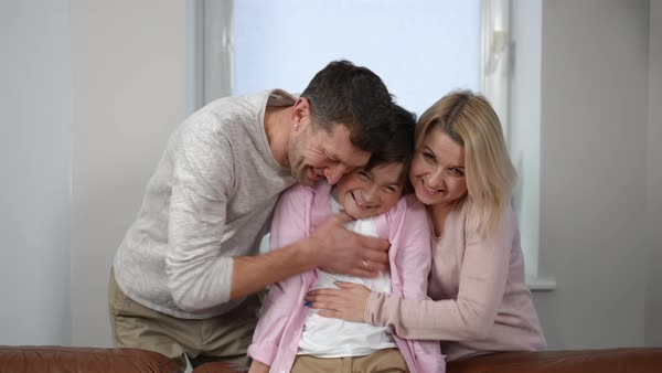 Smiling cute boy posing at home with loving parents hugging child ...