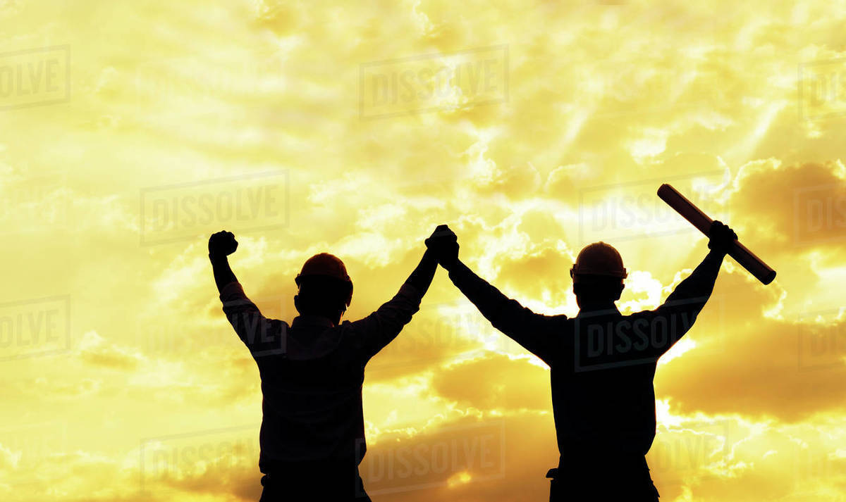 Silhouette of success engineer holding hands together on sunset with ...