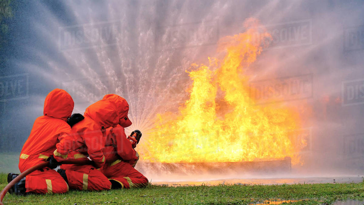 Firefighter fighting with flame using fire hose chemical water foam ...