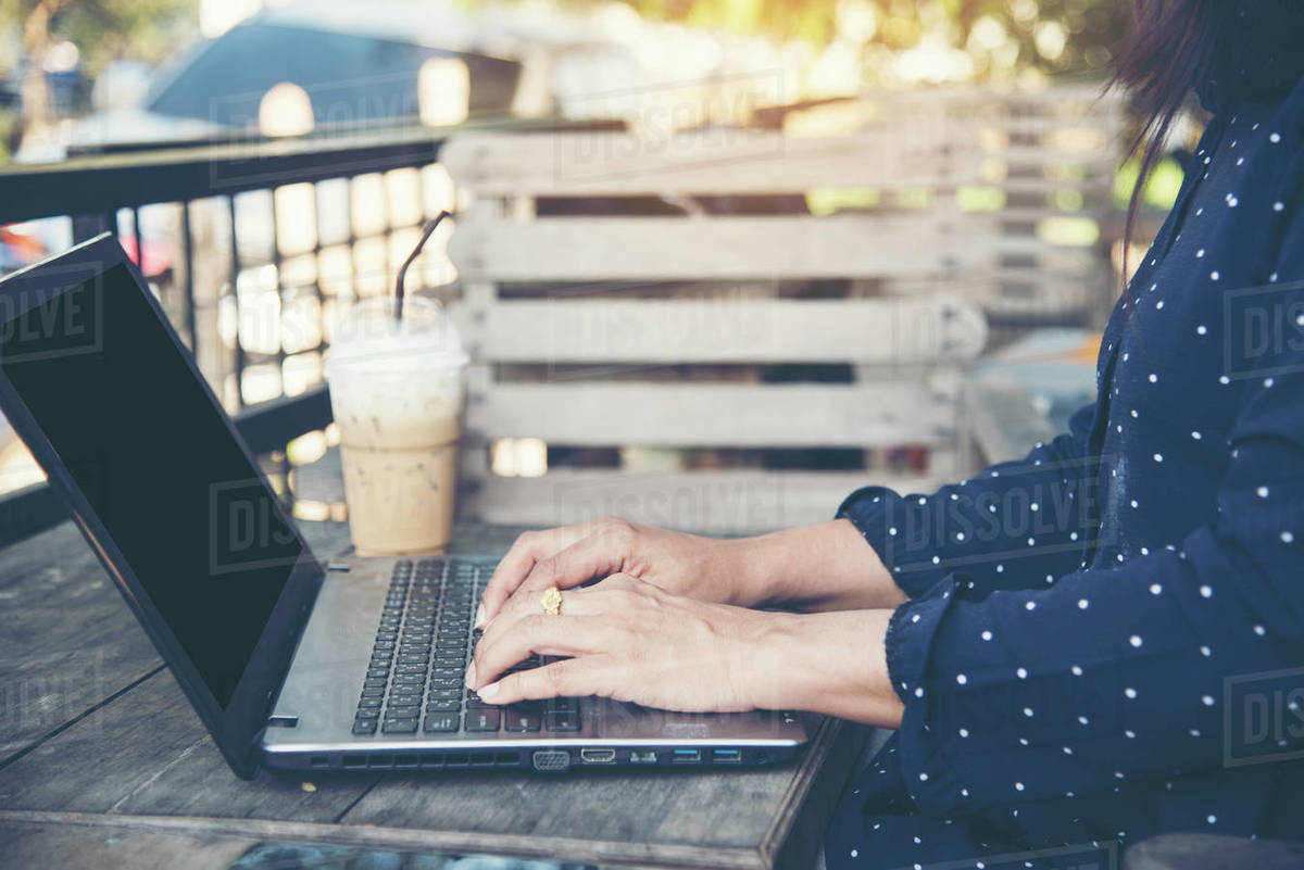 Side view of young smart female using laptop with sunlight. Working ...