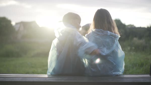 Back view of children hugging in sunrays admiring summer sunset on ...