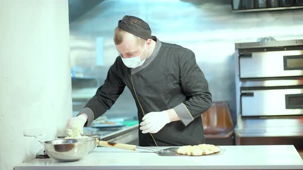 Portrait of concentrated professional male cook in Covid-19 face mask ...
