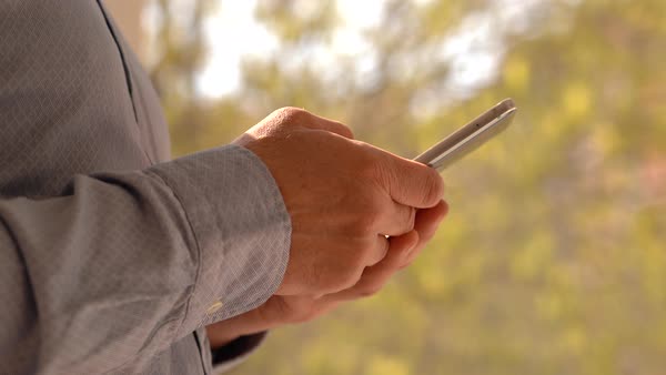 Close up of a man using the touch screen of a mobile phone with a ...