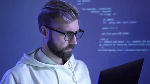 Programmer man with beard and glasses opens laptop to work from home ...