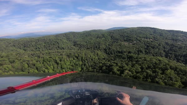 A small red helicopter flies over the forest. The footage was taken ...