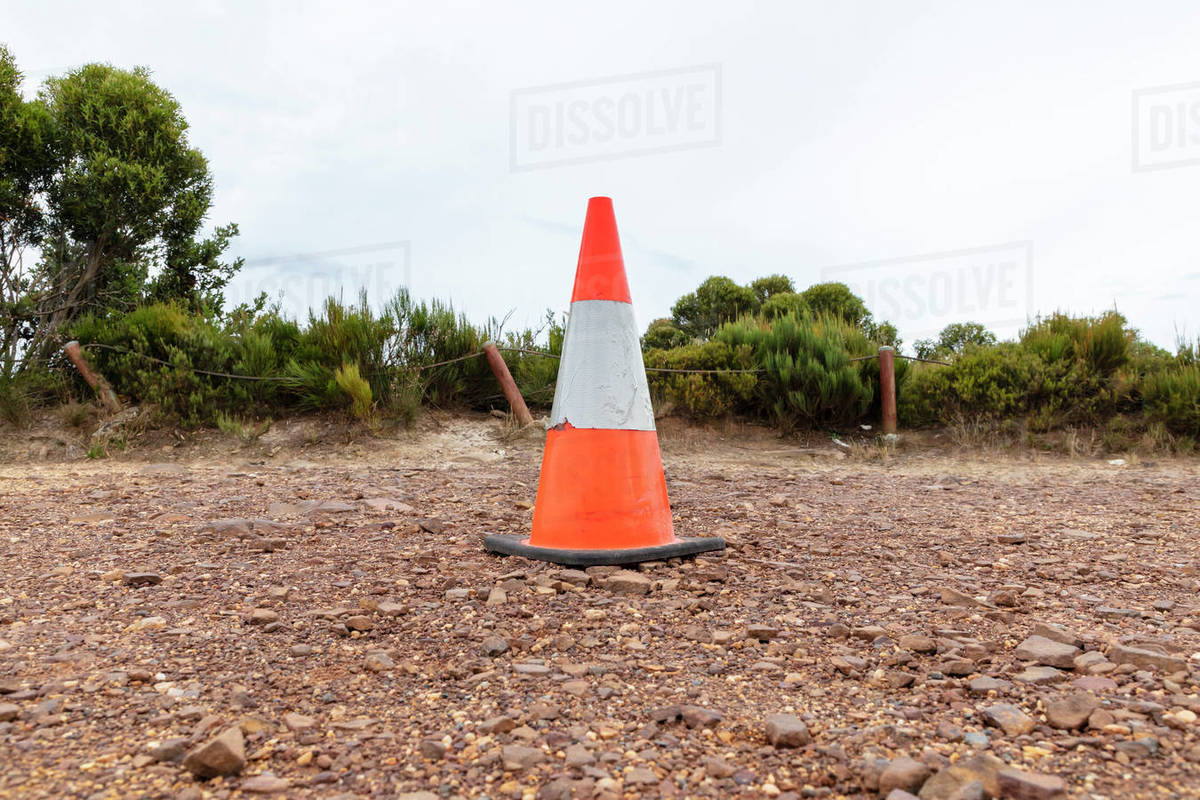 Photograph of an old and damaged orange safety cone with torn ...