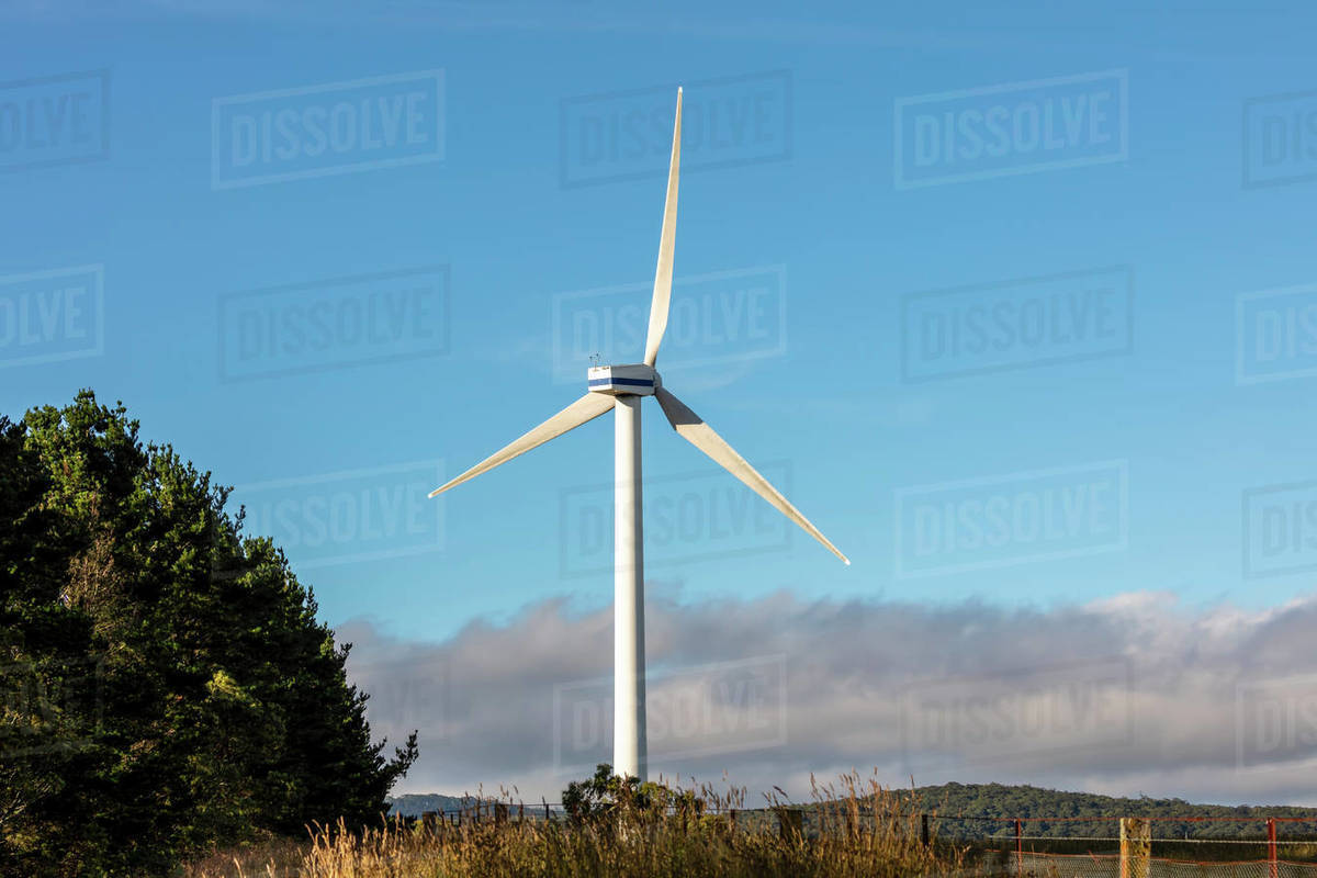 A large three blade industrial wind turbine generating electricity in a ...