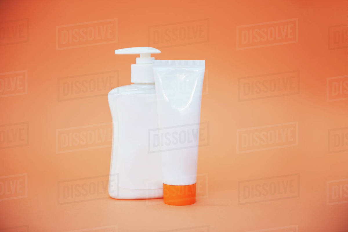 Different cosmetic bottles of cream, soaps, foams or shampoo on orange ...