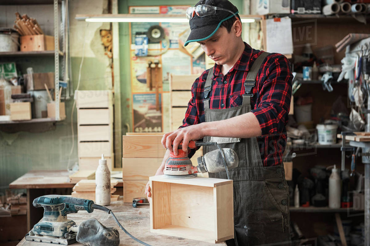 Worker grinds the wood box of angular grinding machine - Stock Photo ...