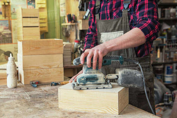Worker grinds the wood box of angular grinding machine - Royalty-free ...