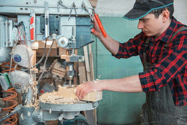 Carpenters with electric drill machine drilling wooden board at ...