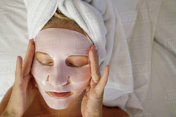 Woman laying in bed wearing a face mask. - Stock Photo - Dissolve